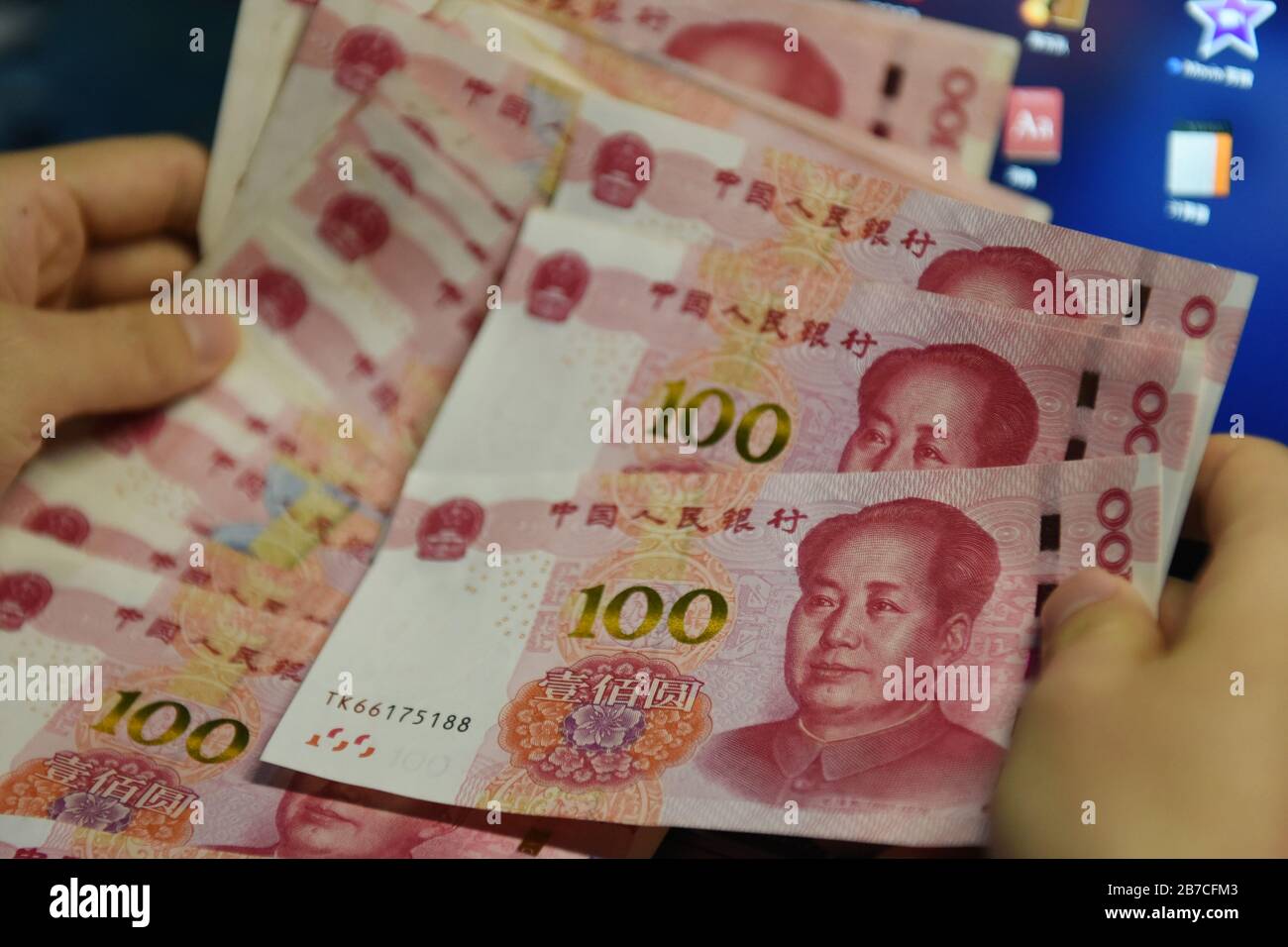 In this photo illustration a man holds 100 RMB notes Stock Photo - Alamy