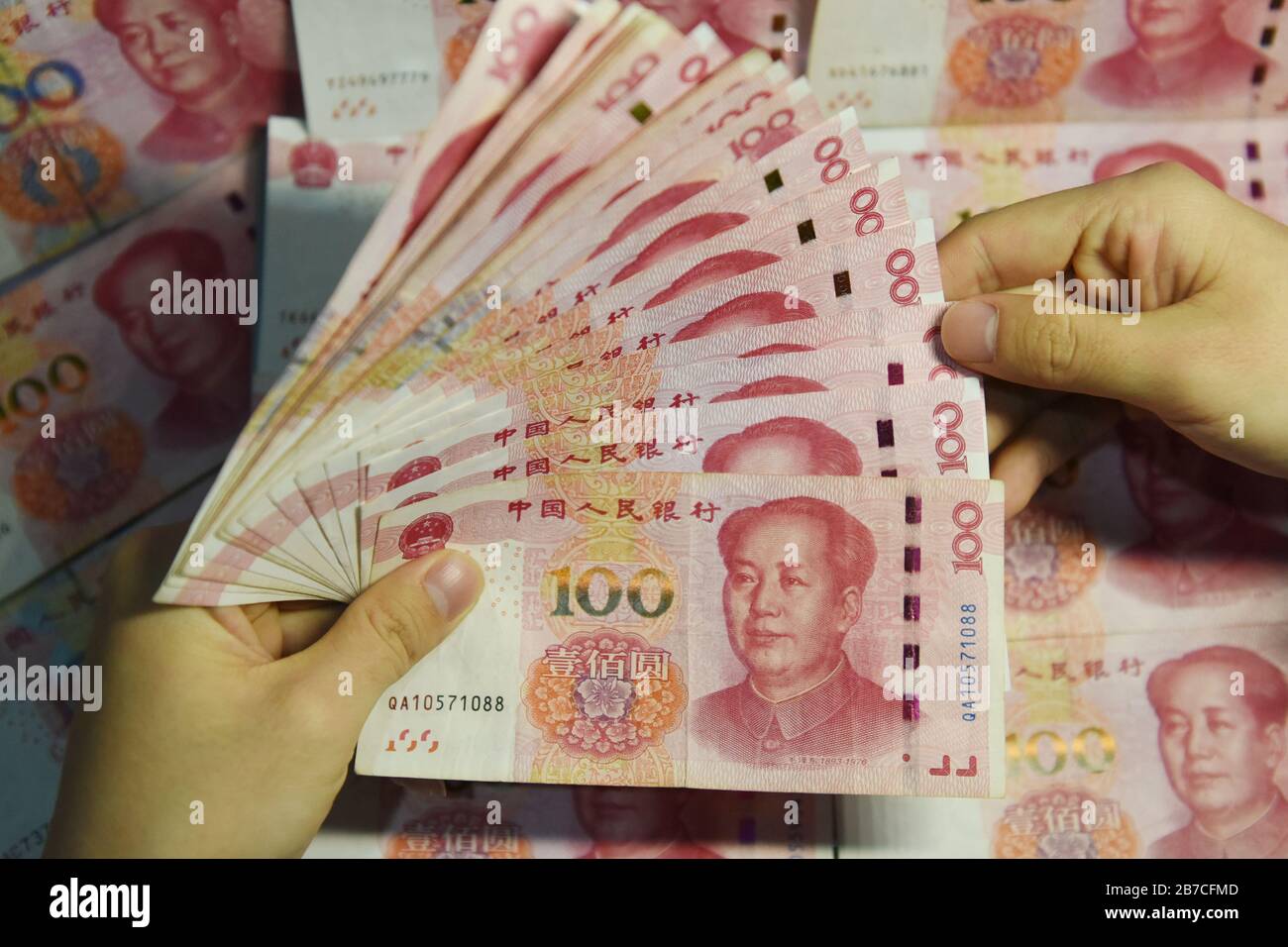 In this photo illustration a man holds 100 RMB notes Stock Photo - Alamy