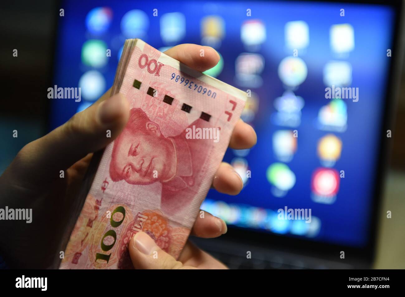 In this photo illustration a man holds 100 RMB notes Stock Photo - Alamy