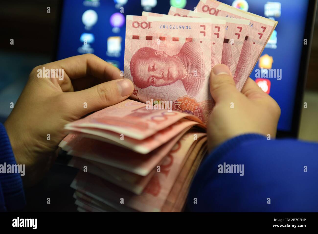 In this photo illustration a man counts 100 RMB notes Stock Photo - Alamy