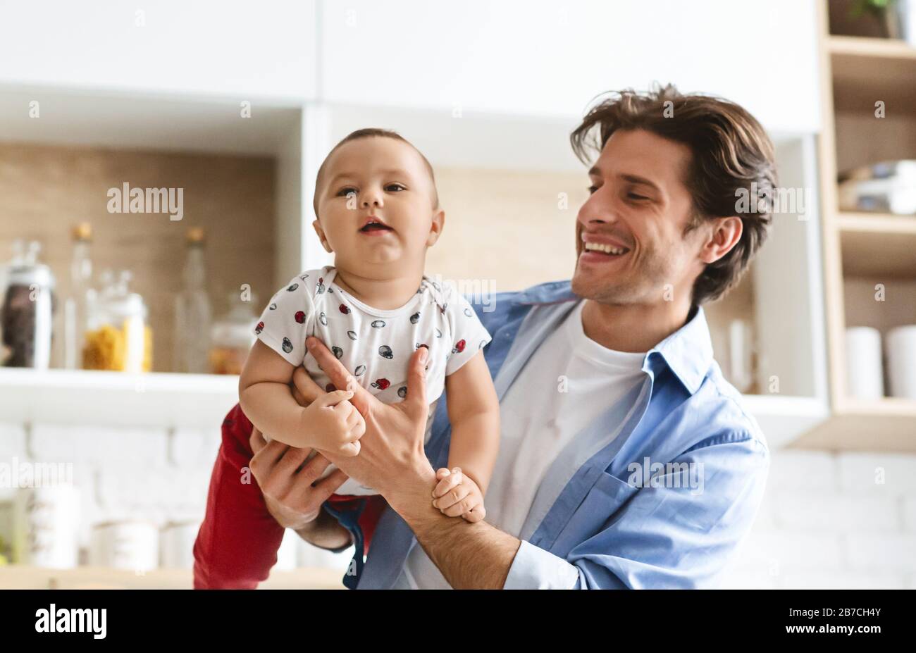 Young father raising his baby son like on plane at kitchen Stock Photo ...
