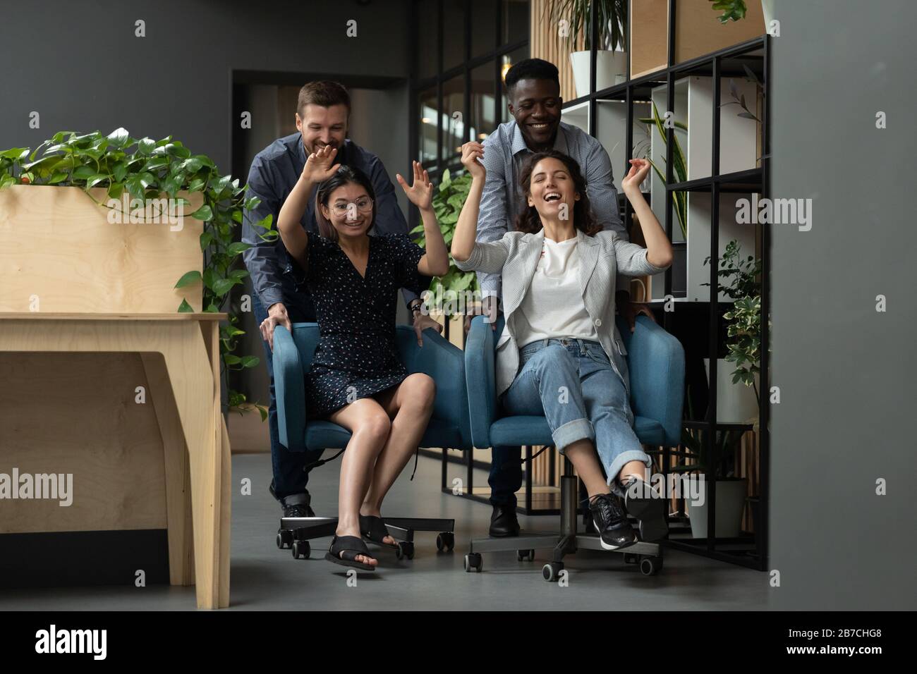 Diverse colleagues having fun, riding on chairs in office Stock Photo ...