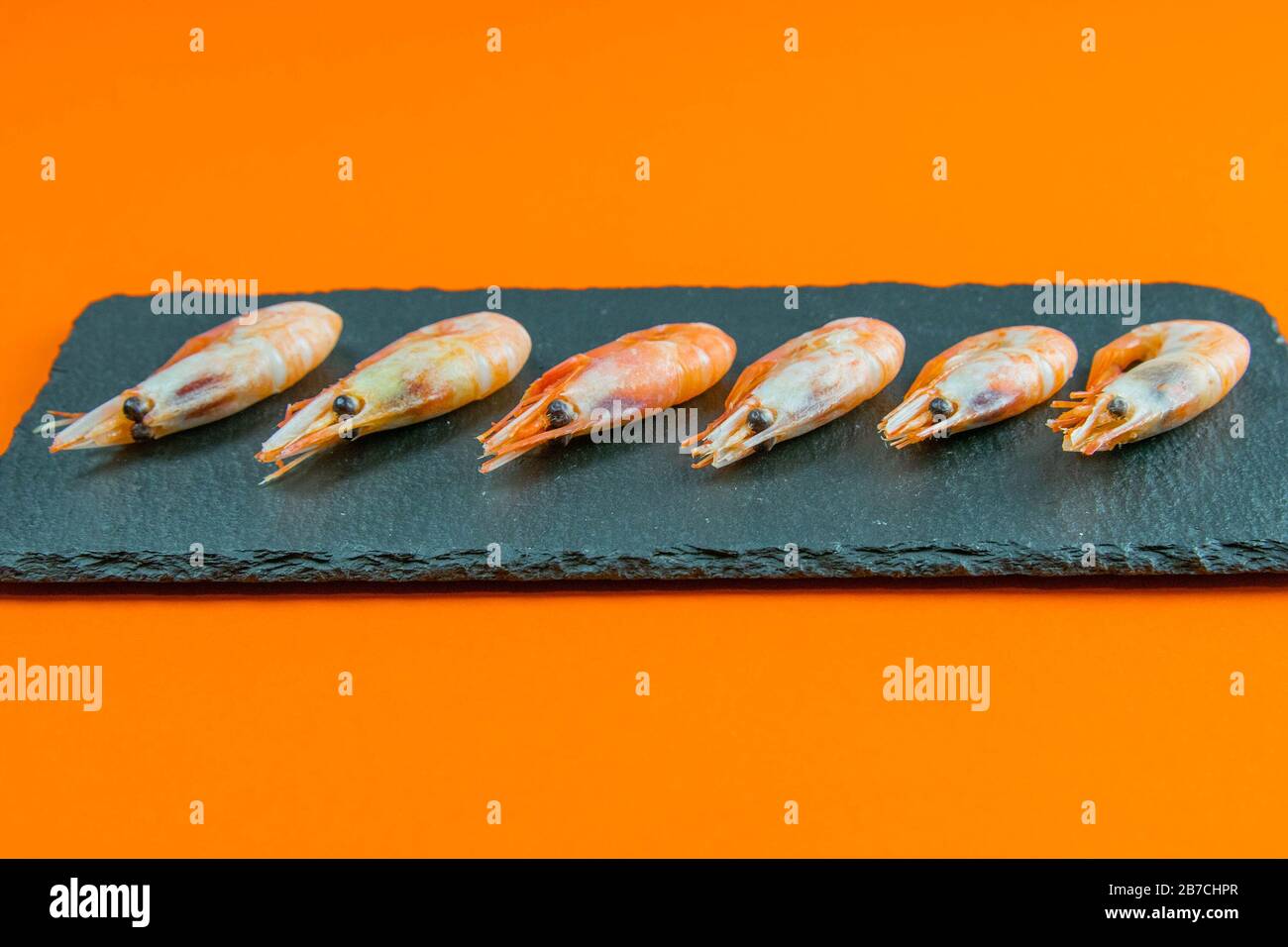 Traditional fried black tiger prawn stand on a slate board which stands ...