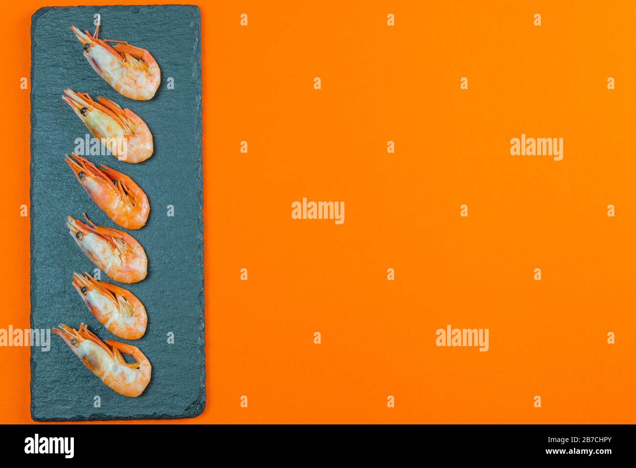 Traditional fried black tiger prawn stand on a slate board which stands ...