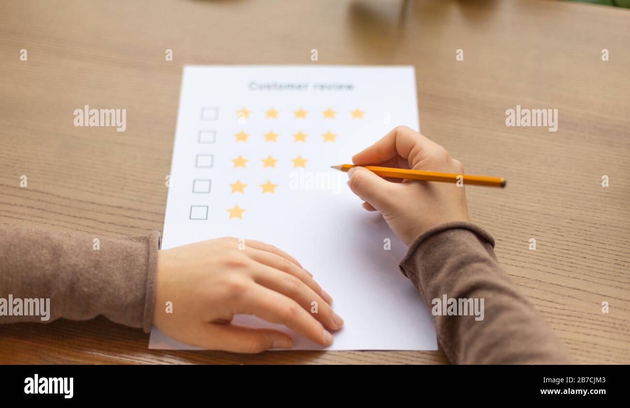 Woman thinking about customer review sheet, wooden background Stock ...