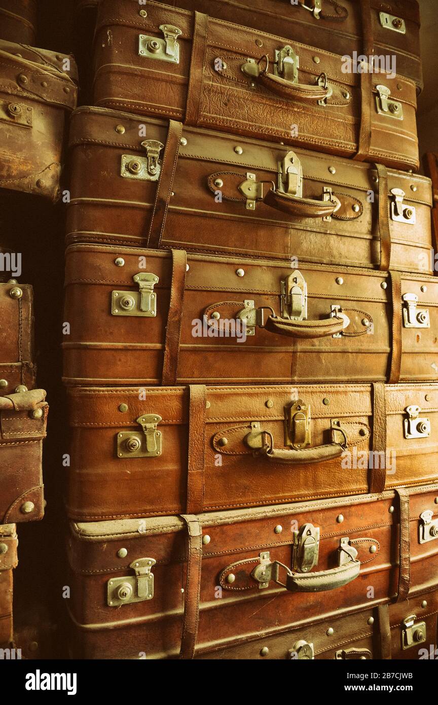 Stack of retro brown leather suitcases covered by dust in dressing room ...