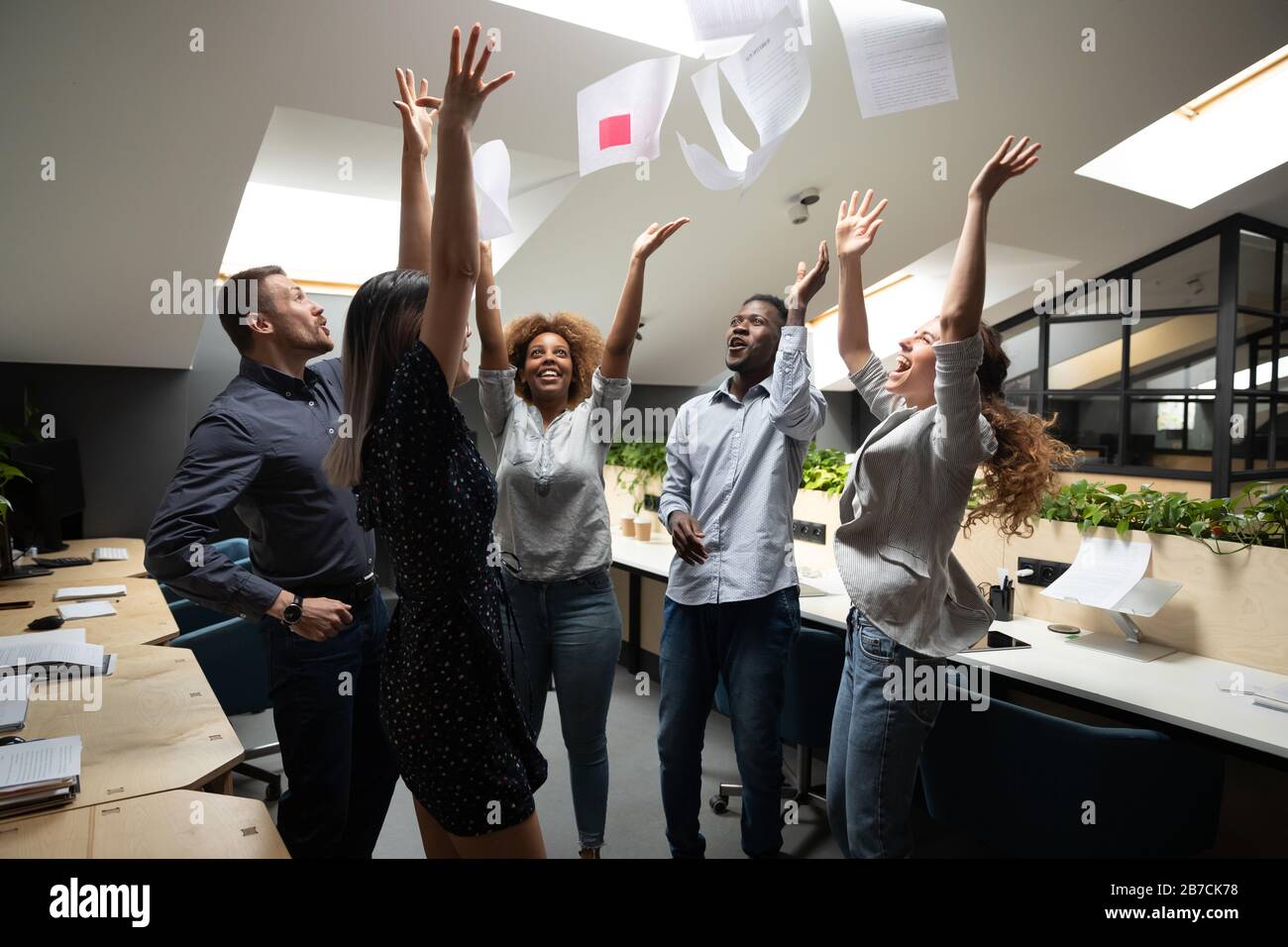 Happy excited diverse employees throwing papers, celebrating success ...