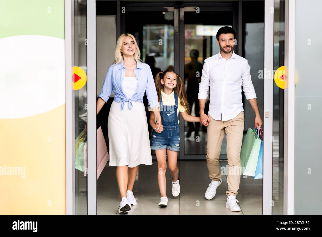 Joyful Parents And Daughter Holding Bags Leaving Shopping Mall Stock ...