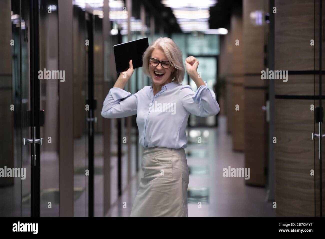 Happy middle-aged businesswoman celebrate success in office Stock Photo ...