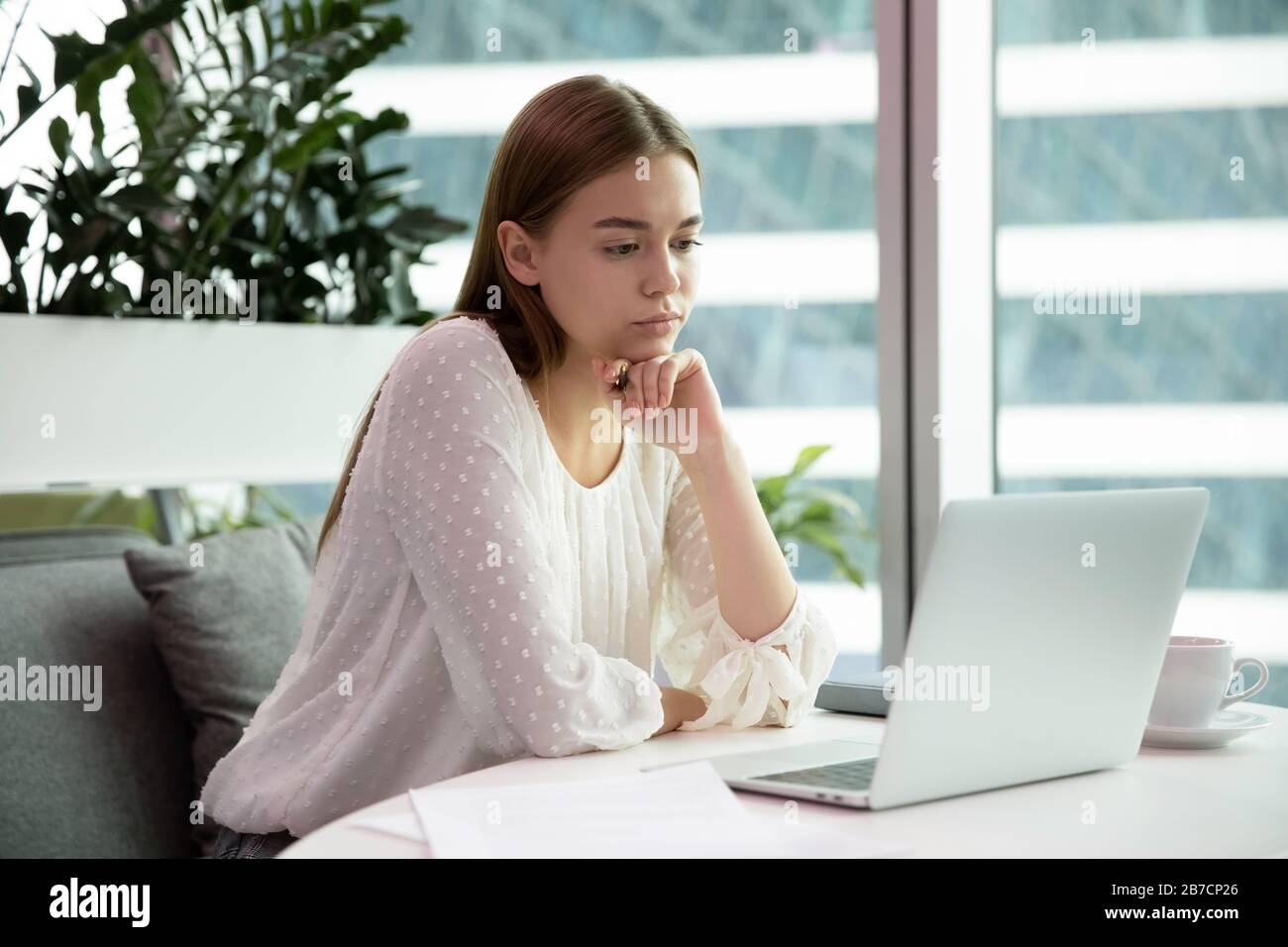 Pensive millennial female work on laptop thinking Stock Photo - Alamy