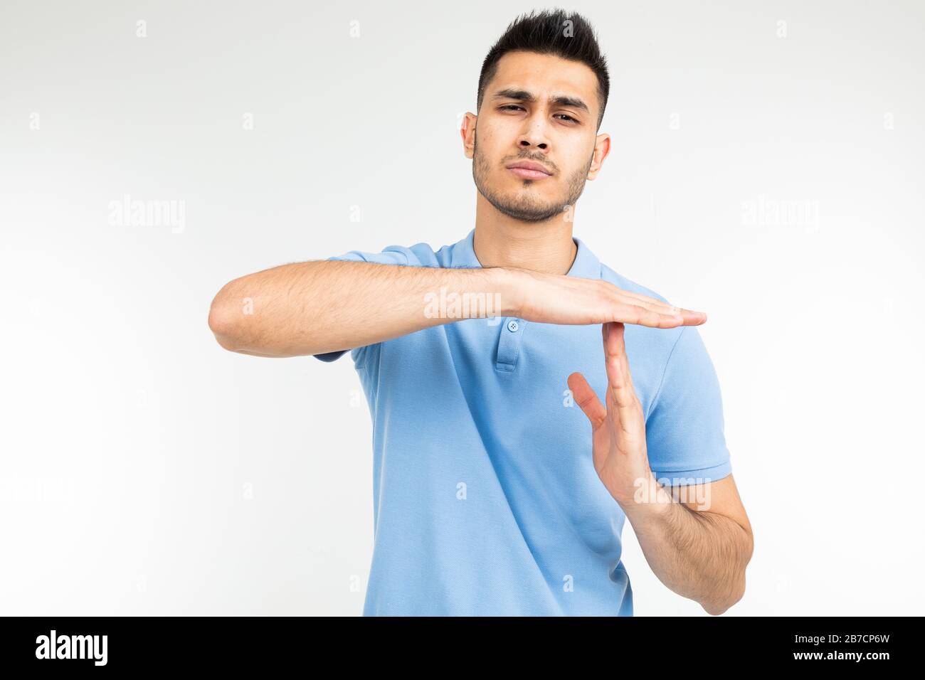 a man in a blue T-shirt shows the letter t with his hands against a ...