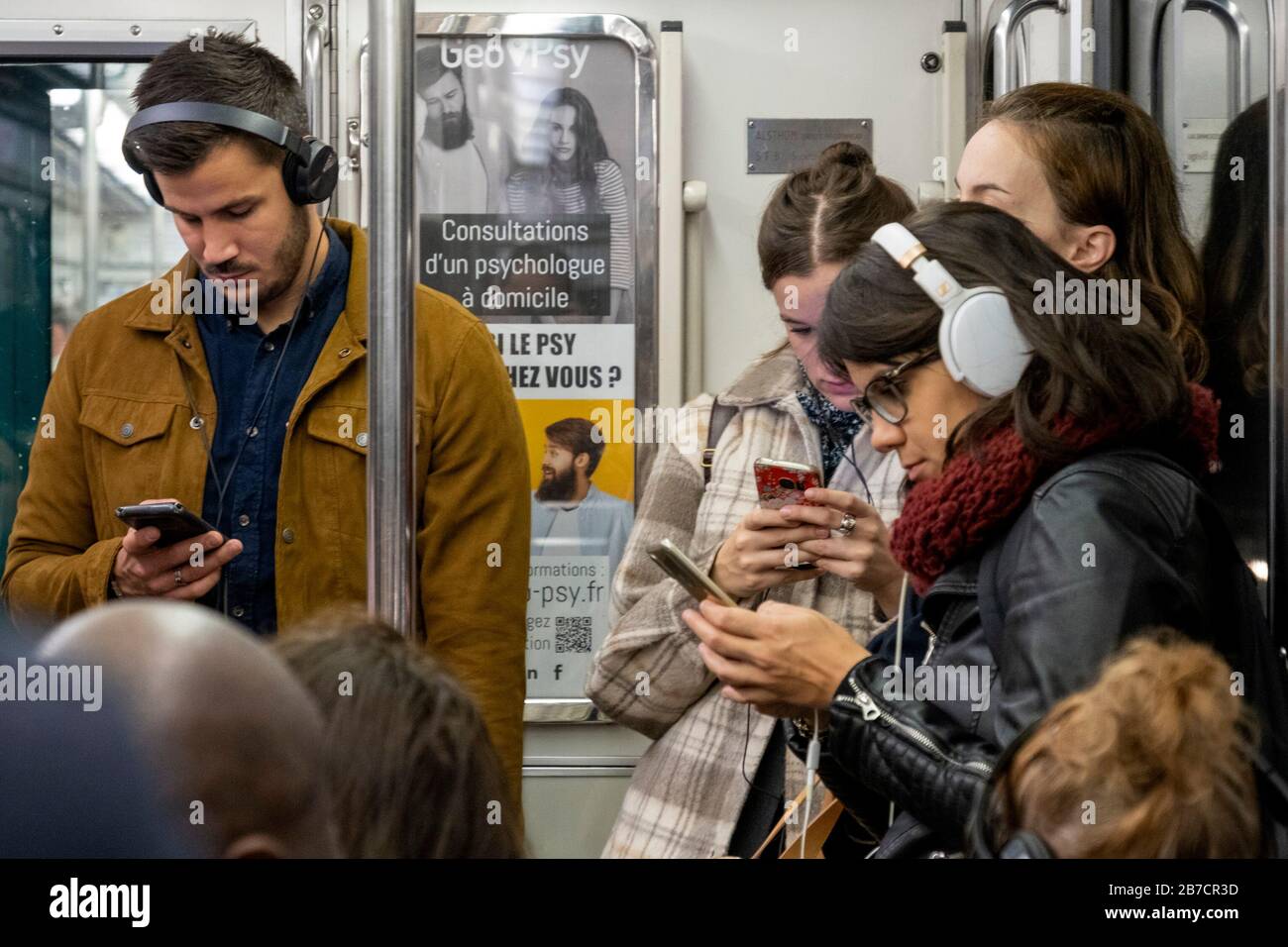 Young people standing and using smartphones in the parisian metro ...