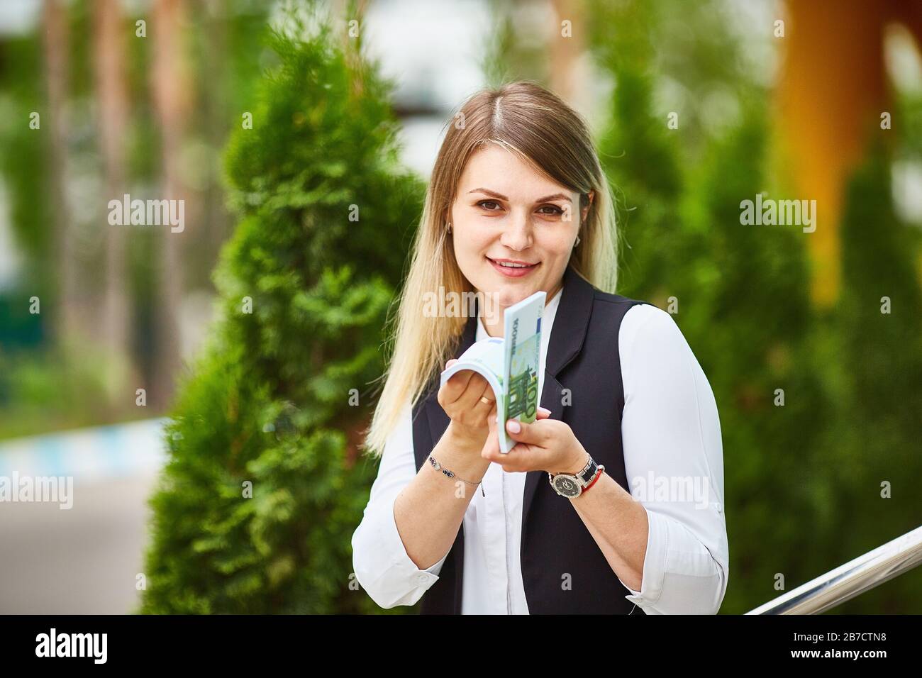 Girl holding a stack of euro banknotes and smiling. Business, income ...