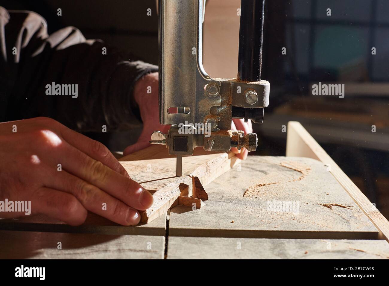 close-up of the hands of a worker sawing wooden boards on a band saw ...
