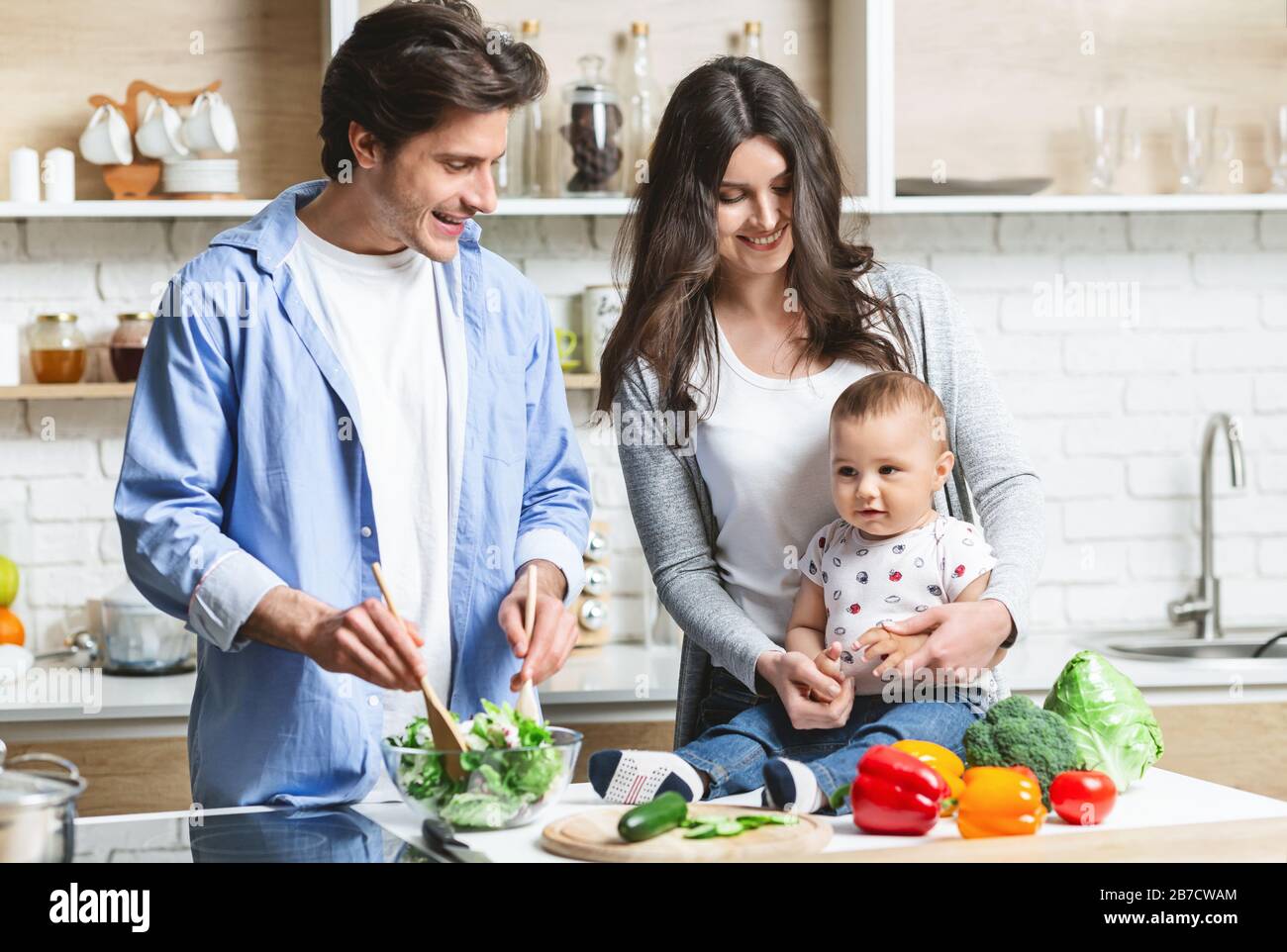 Parents with baby cooking organic healthy lunch at kitchen Stock Photo ...