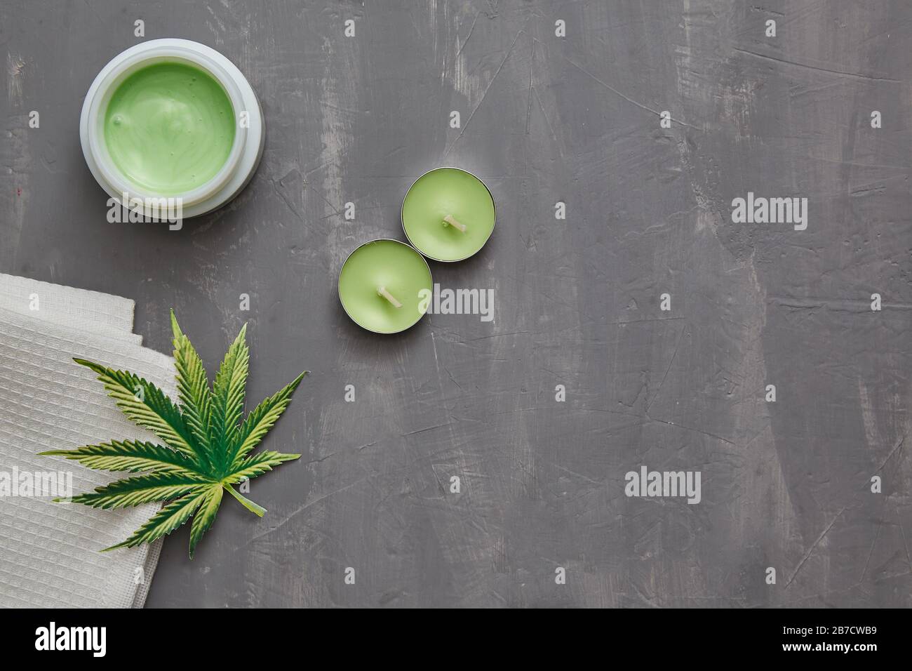 Cannabis hemp cream with marijuana leaf and candles on a gray concrete ...