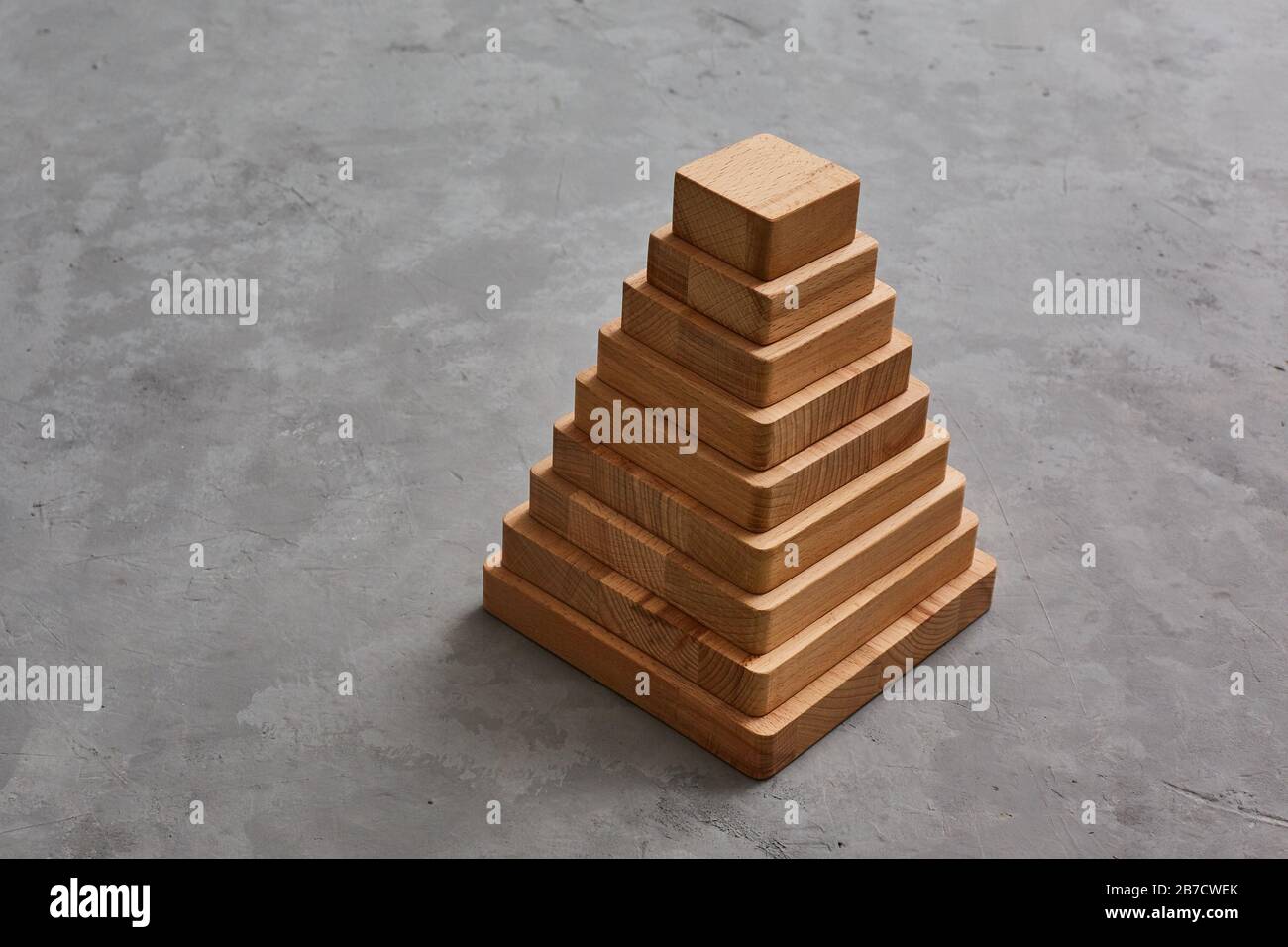 Wooden toy pyramid on grey concrete background. Copyspase Stock Photo ...