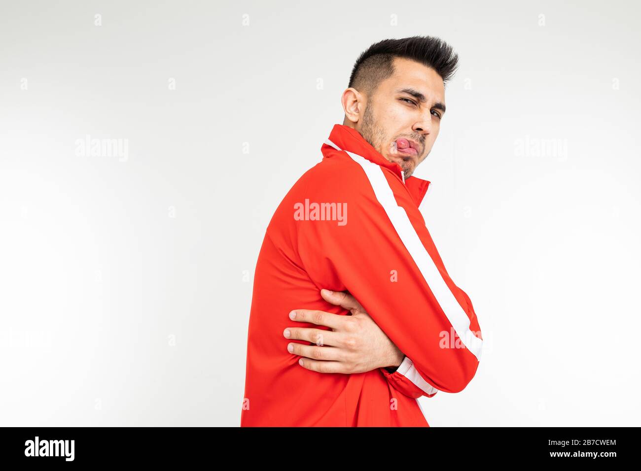 offended man in a sports red suit hugs himself and shows tongue on a ...