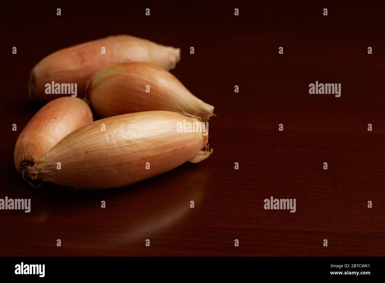 Long golden shallots on brown wood table Stock Photo - Alamy