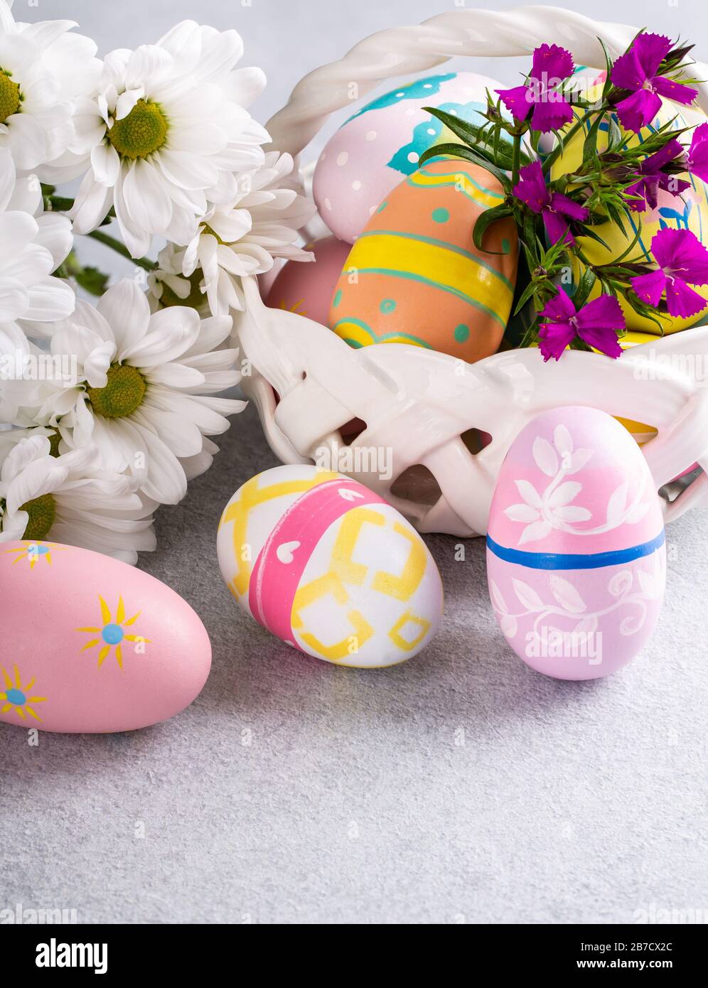 Closeup of colorful daisy flowers and easter eggs on a table with copy ...