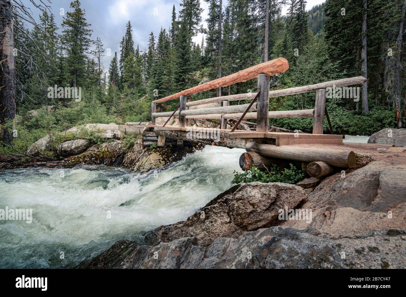 Wooden footbridge over ice melt raging river in Grand tetons mountains ...