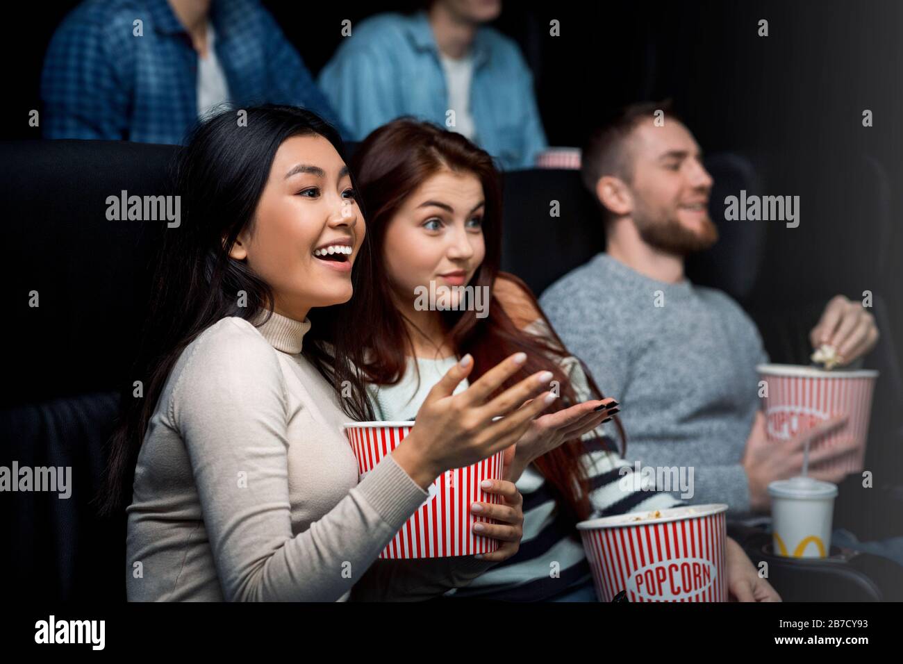 Weekend getaway. Smiling girls enjoying their movie night in cinema ...