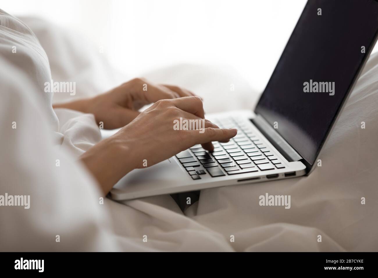 Young woman using computer in bed after waking up Stock Photo - Alamy