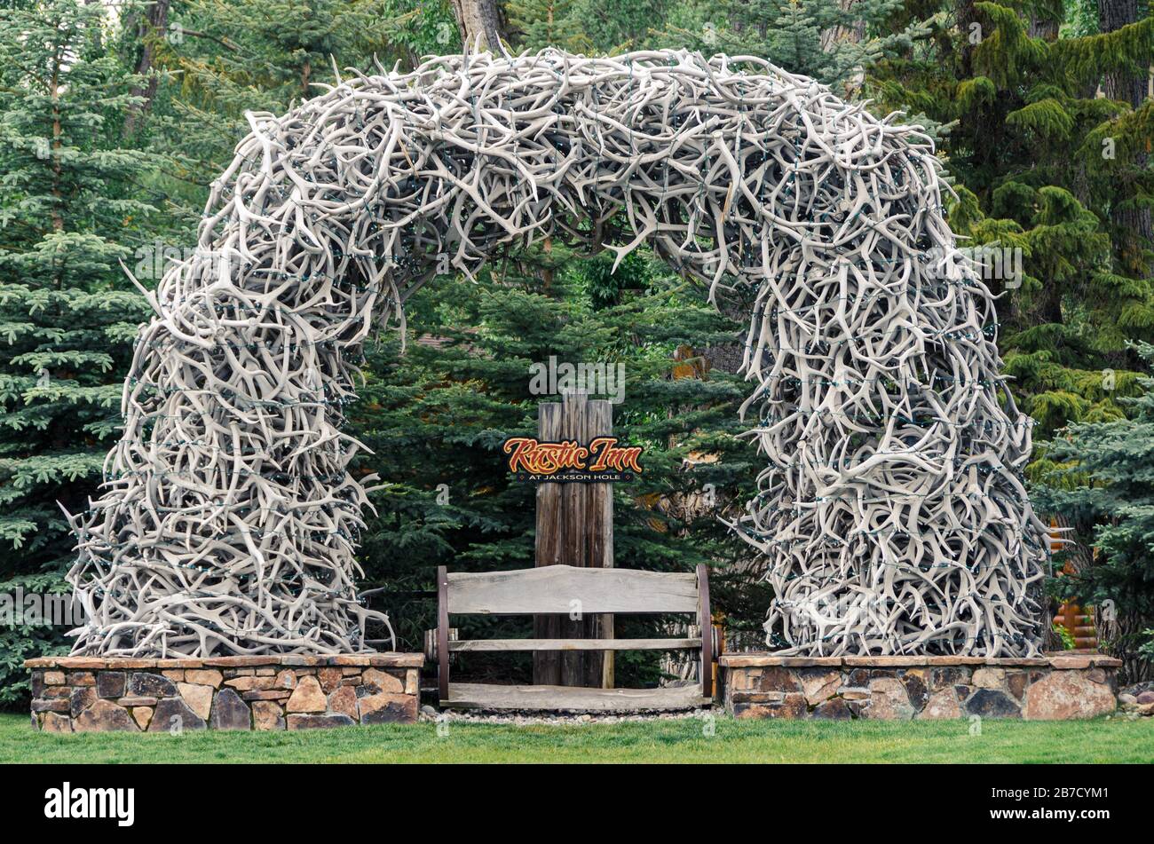 Elk antler arch with wooden seat underneath and sign for Rustic Inn ...
