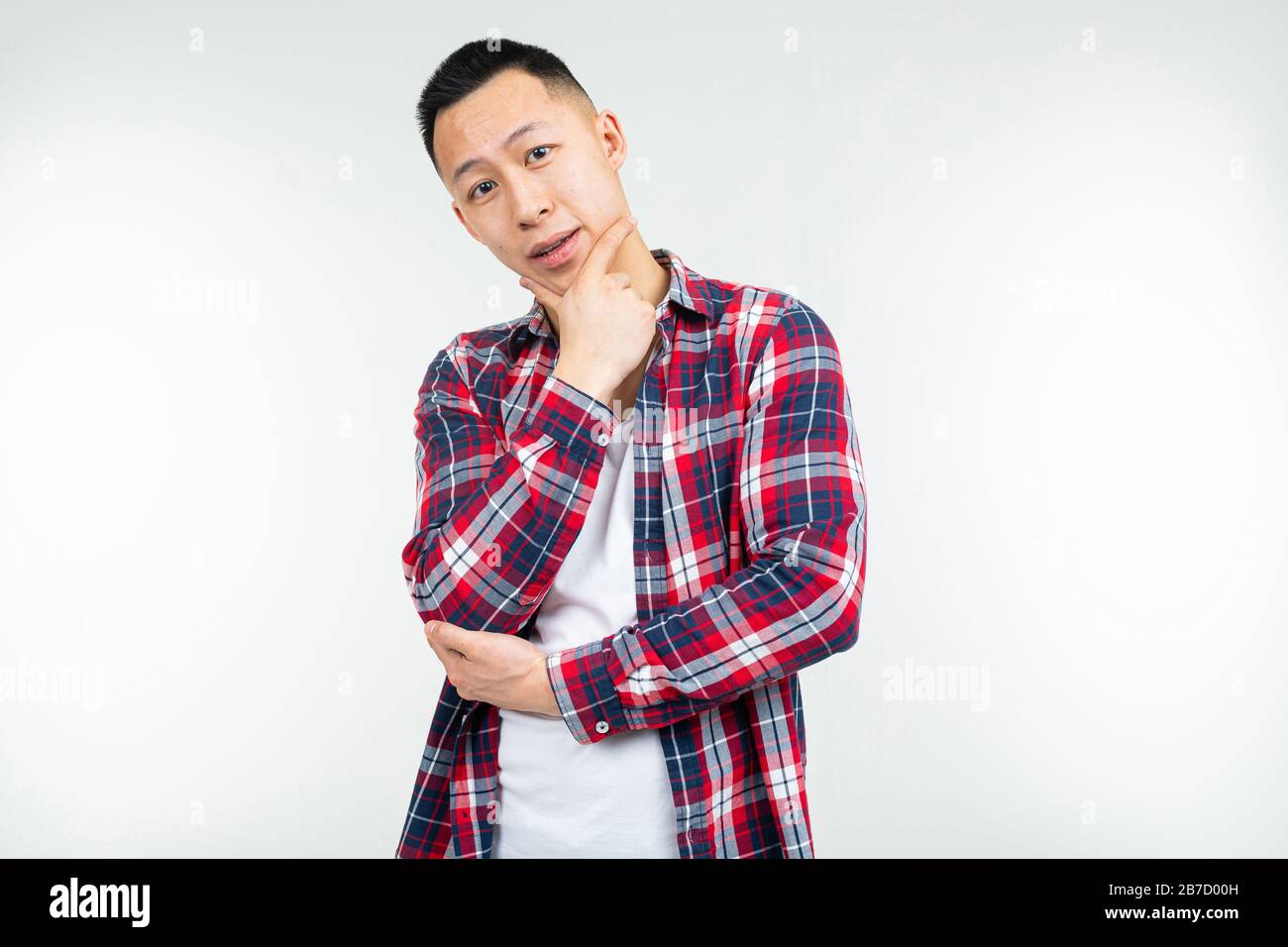 Confident Asian man in a plaid shirt wide open on a white studio ...