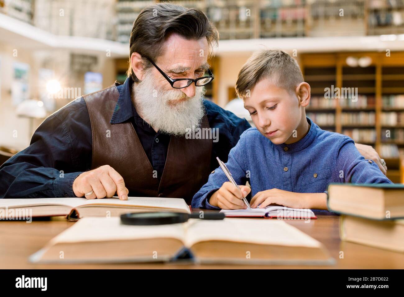 Happy little boy doing school homework with old man, sitting at the ...