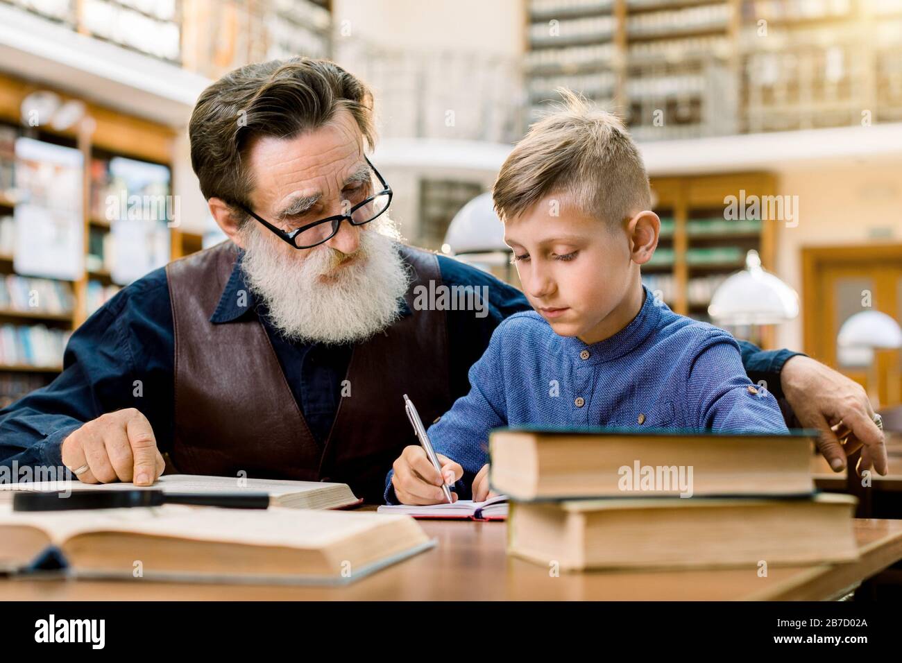 Senior man teacher or grandfather teaching little boy, his grandchild ...