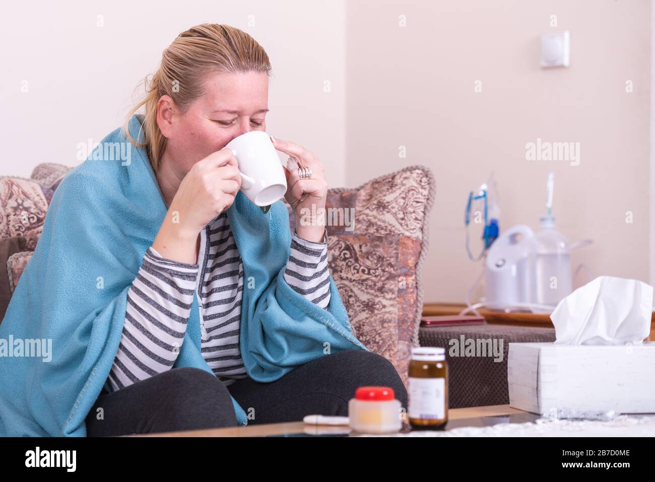 A very sick woman with temperature drinks warm tea Stock Photo - Alamy