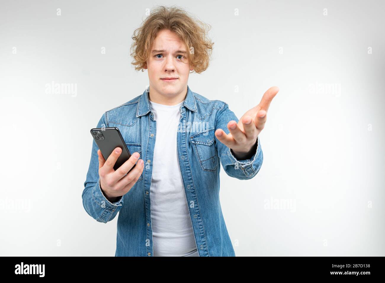 confused guy with a phone in his hand isolated on a white background ...
