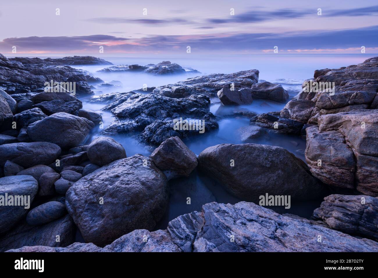 A pre-dawn photograph of misty waves crashing on the rocks by the South ...