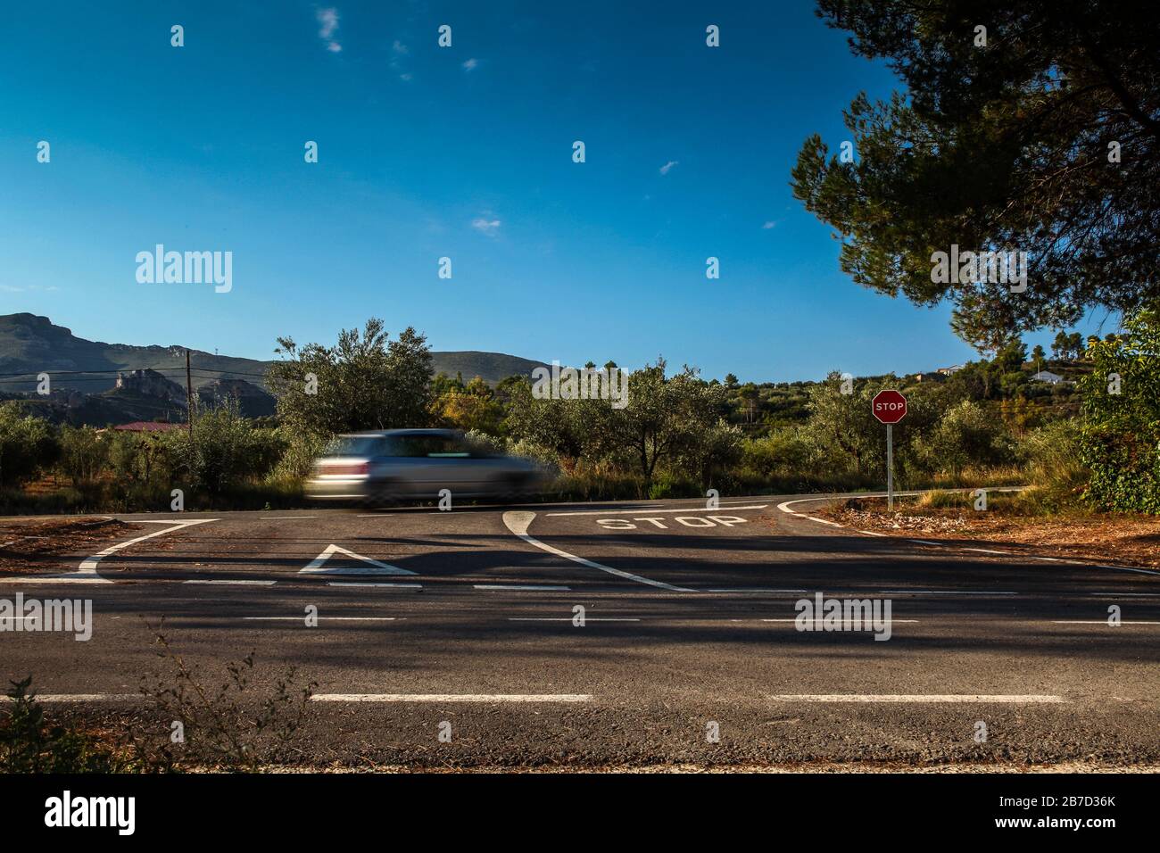Road junction with stop sign and car in a rural road Stock Photo - Alamy