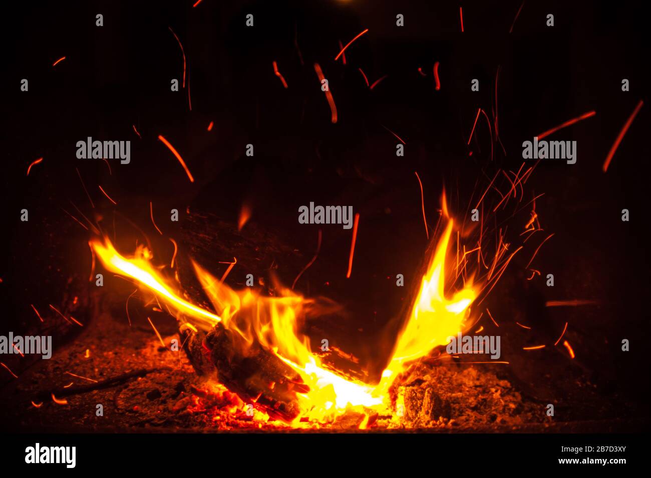 Burning wood flames with sparks in the dark Stock Photo - Alamy