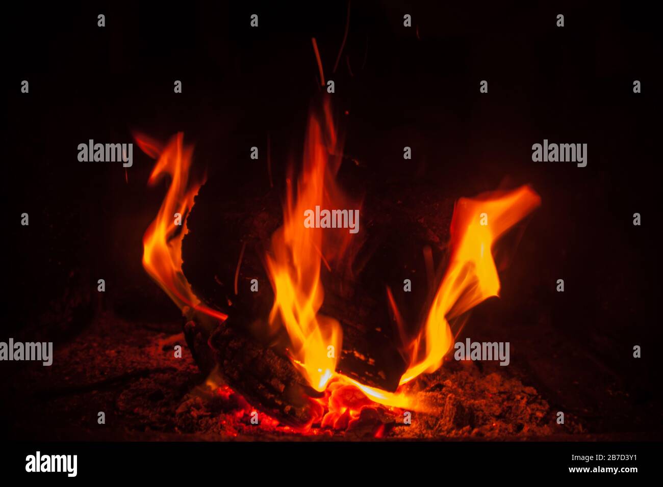 Burning wood flames with sparks in the dark Stock Photo - Alamy