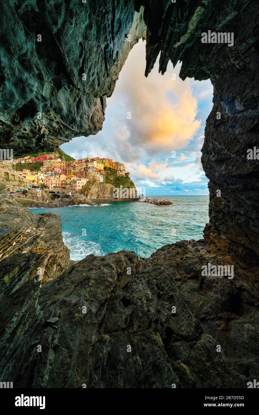 Manarola at sunset seen from hole of cave, Cinque Terre, La Spezia ...