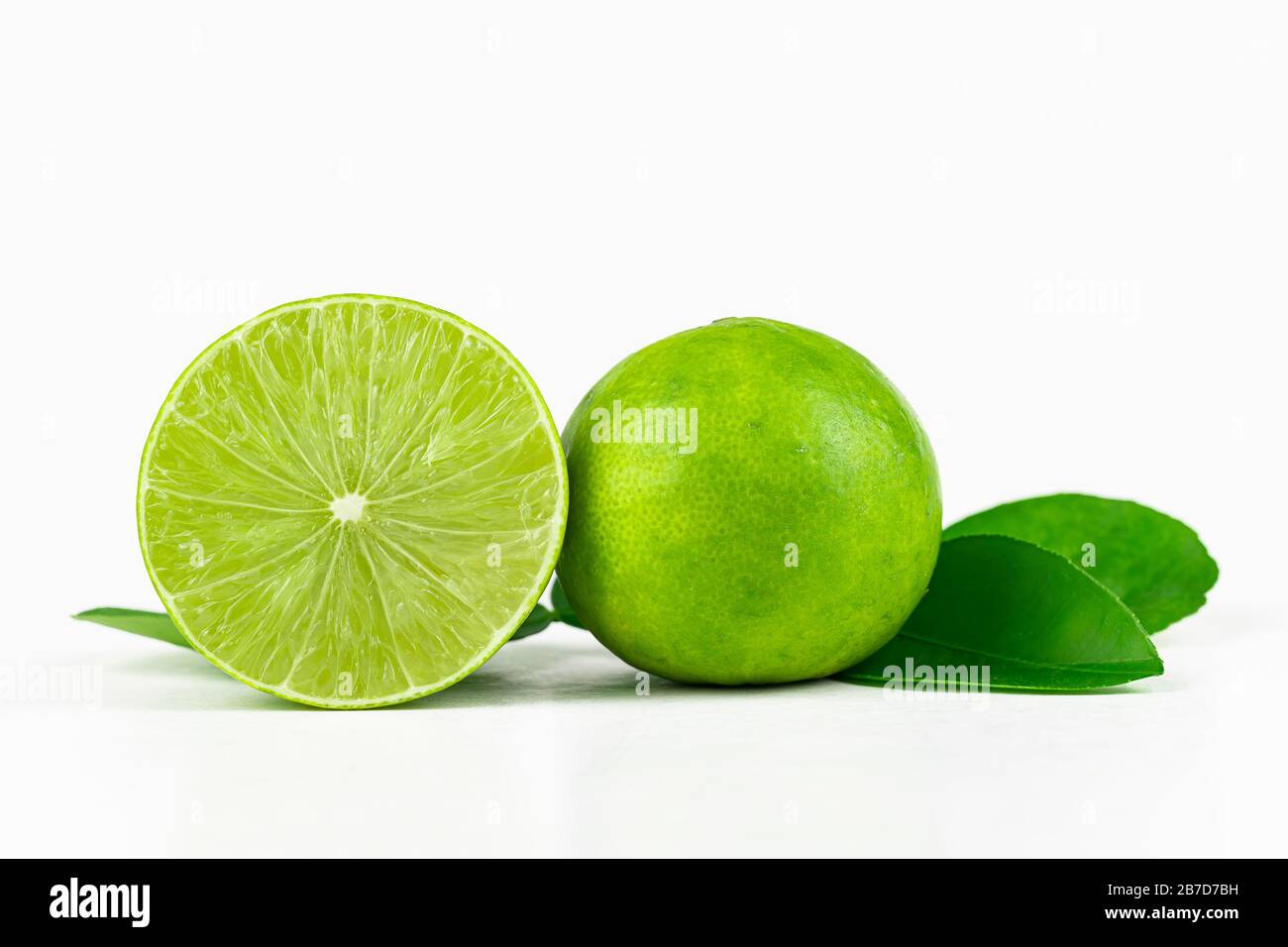 Green lime with cut in half and green leaves isolate on white ...