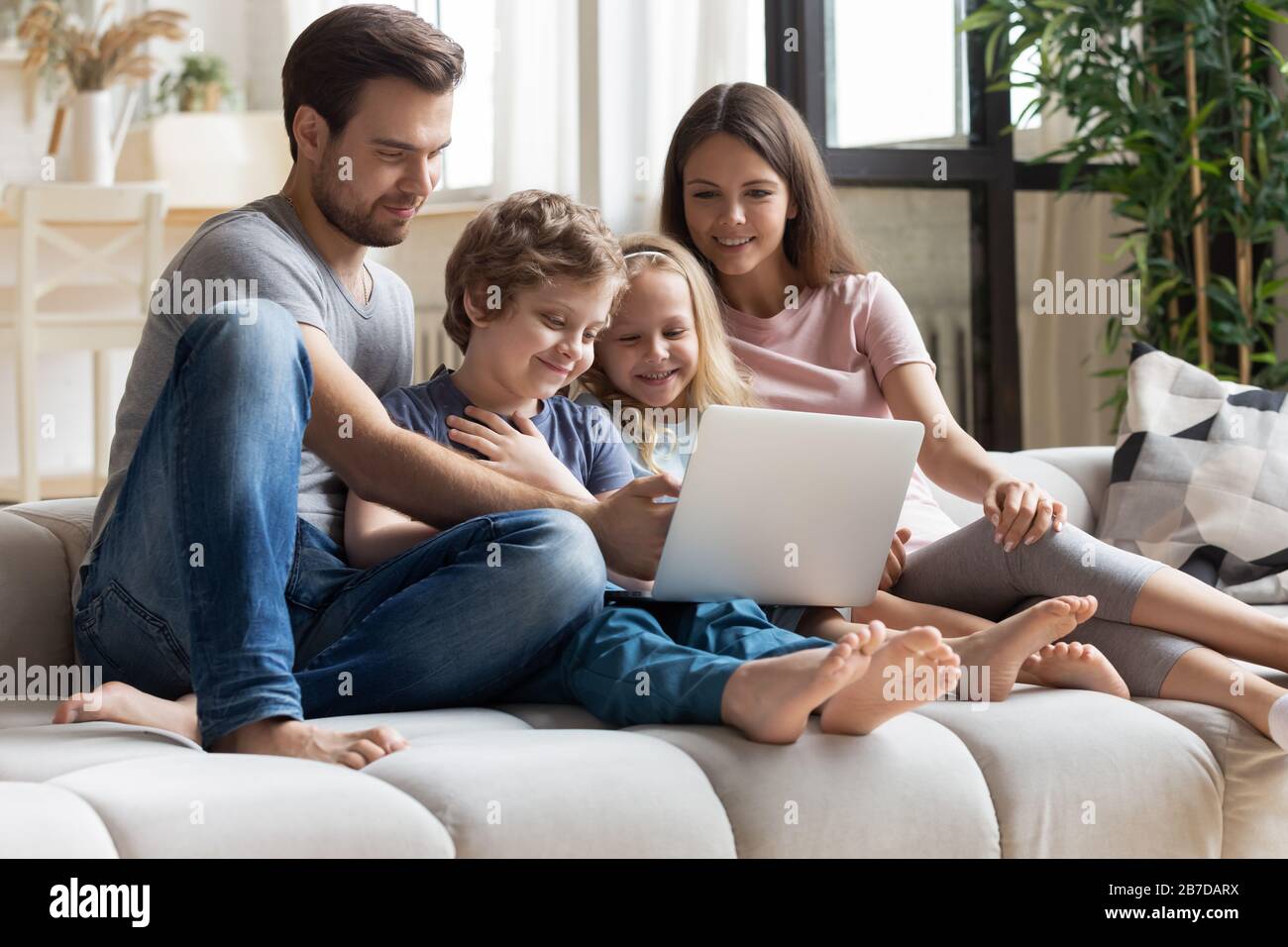 Happy family with small children watching video on laptop Stock Photo ...