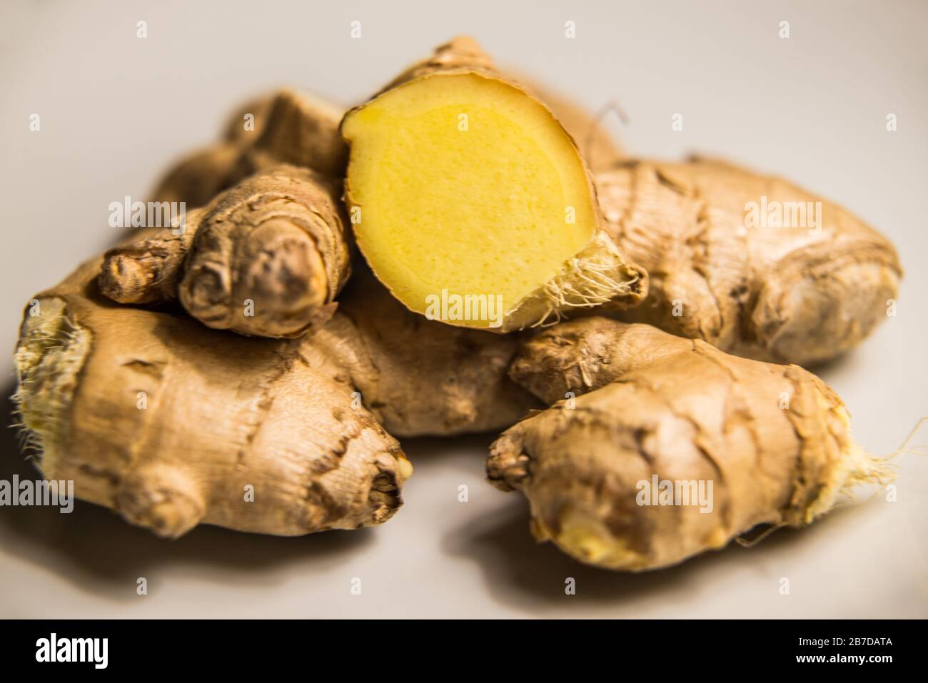 Some cut ginger roots on a white cutting board Stock Photo - Alamy