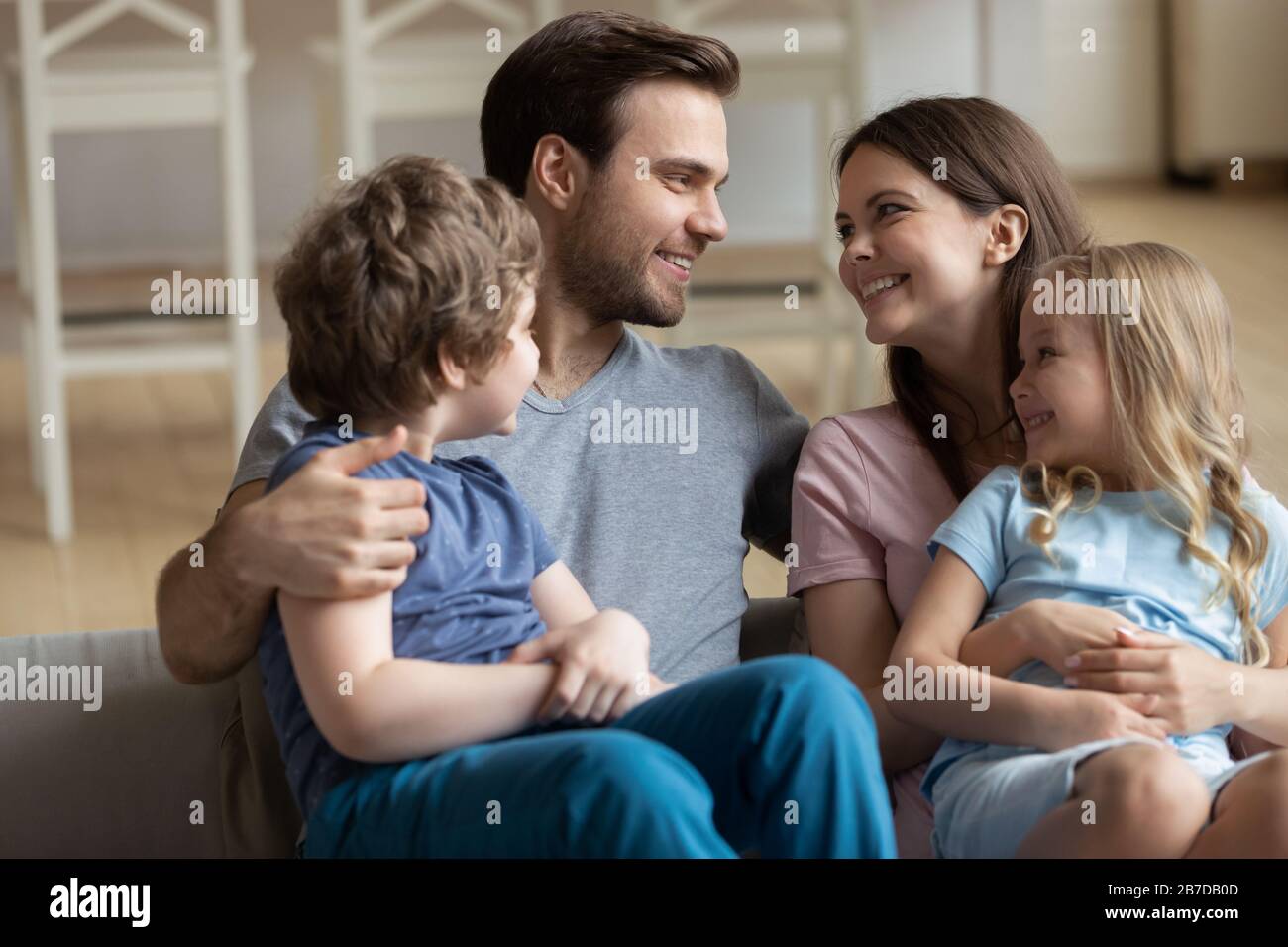 Happy parents cuddle relax with small kids Stock Photo - Alamy