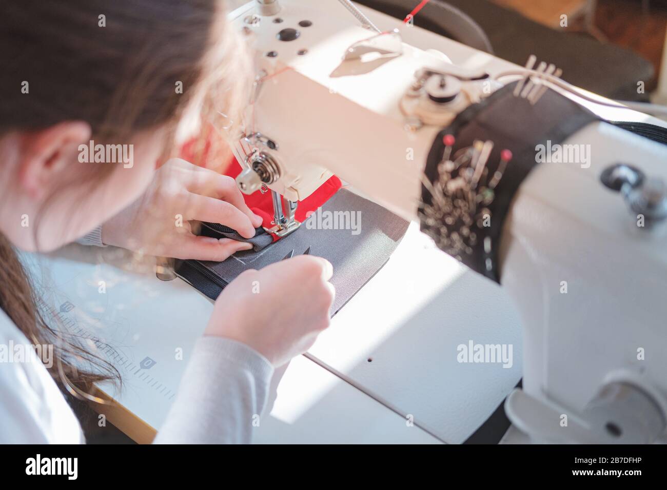 Seamstress doing precise work, shoulder view. Needlewoman at overlock ...