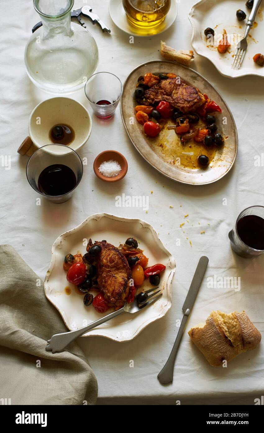 Overhead image of family dinner table with roasted fish, tomatoes ...