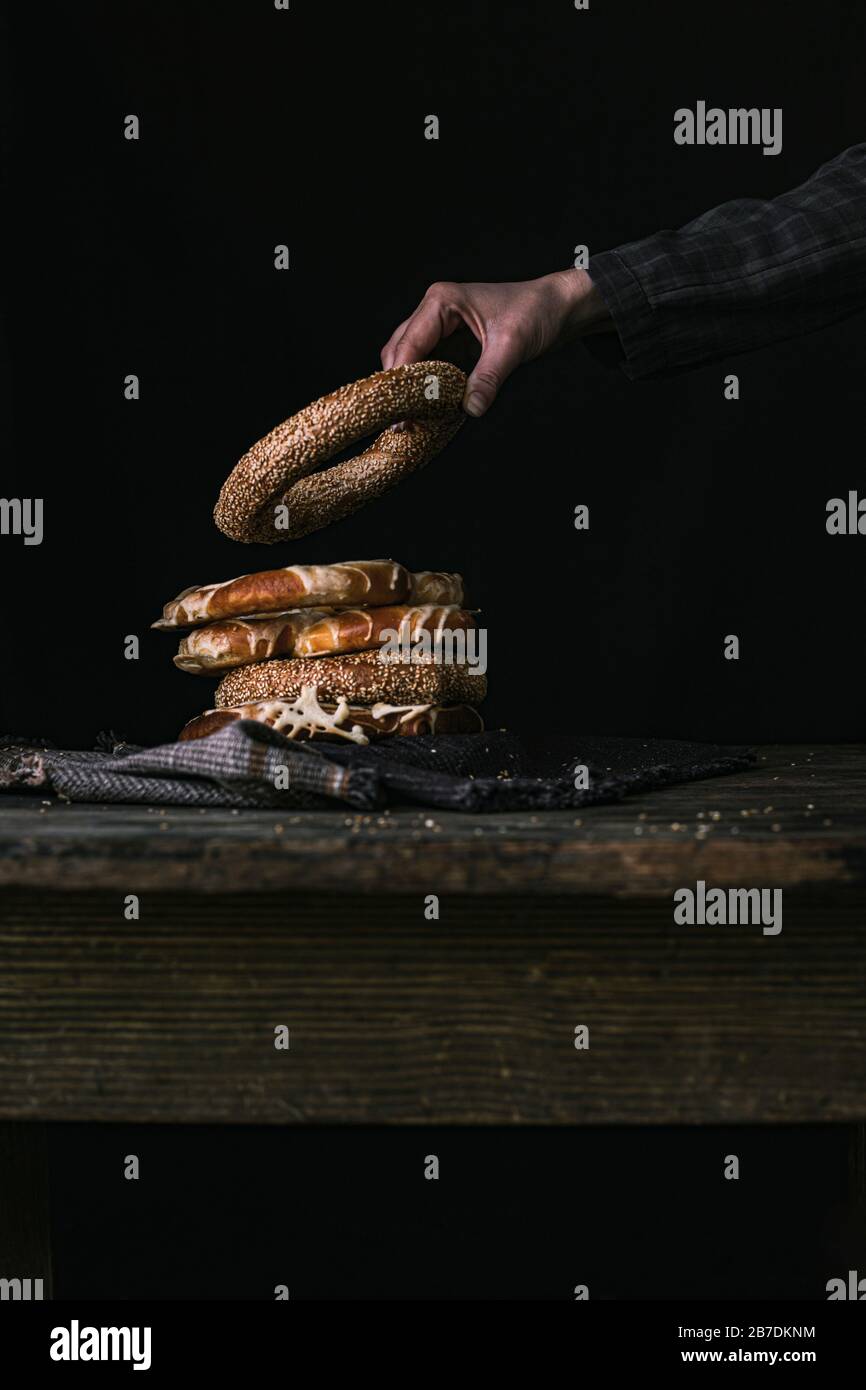 A Hand Taking a Bagel on a Black Background Stock Photo - Alamy