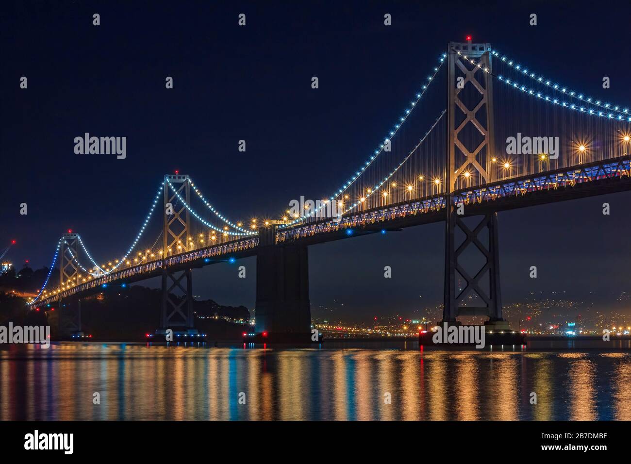 San Francisco Bay Bridge on a clear night, lit up by yellow and blue ...