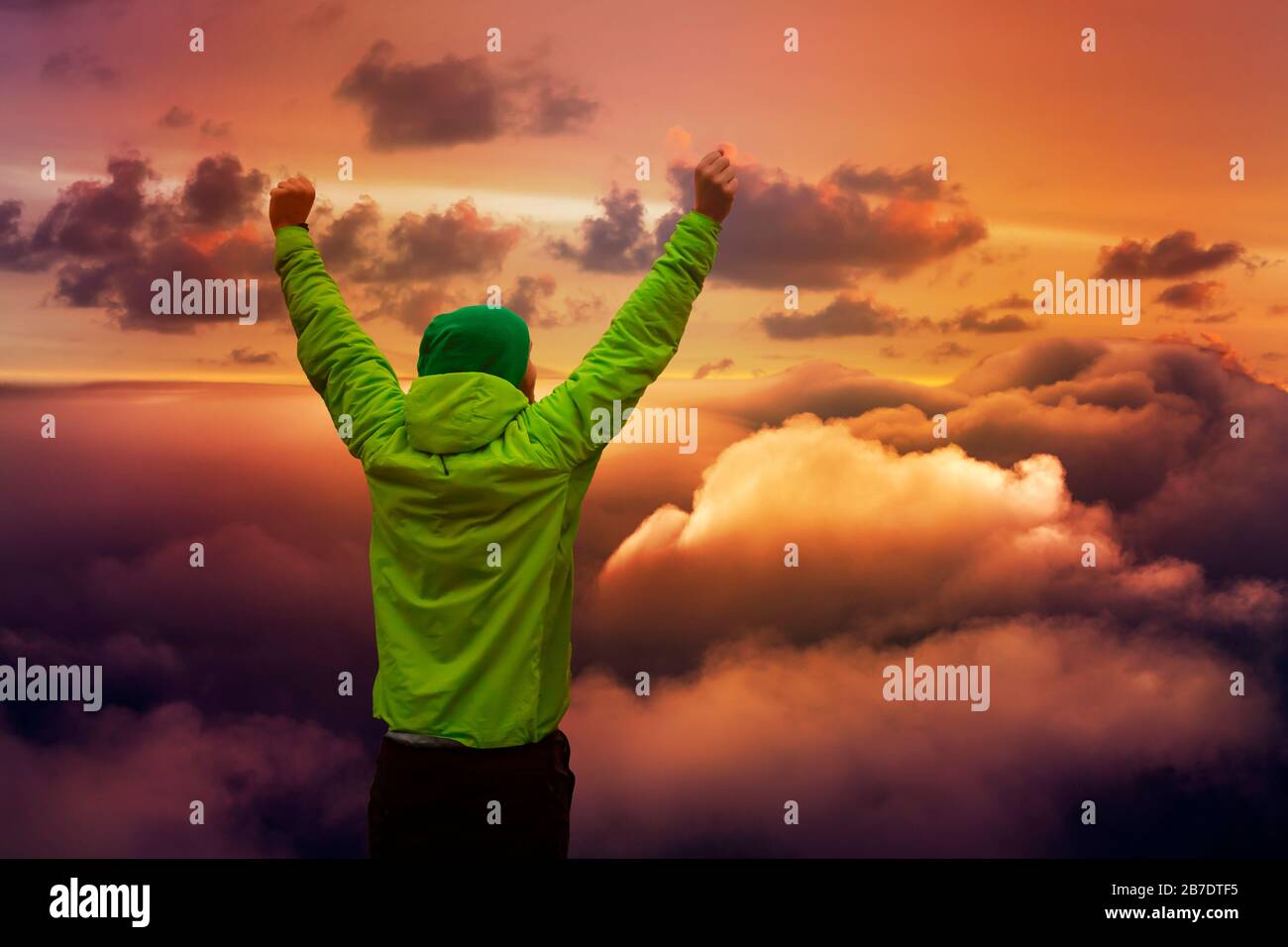 Adventurous friends on top of mountain with hands up during a colorful ...
