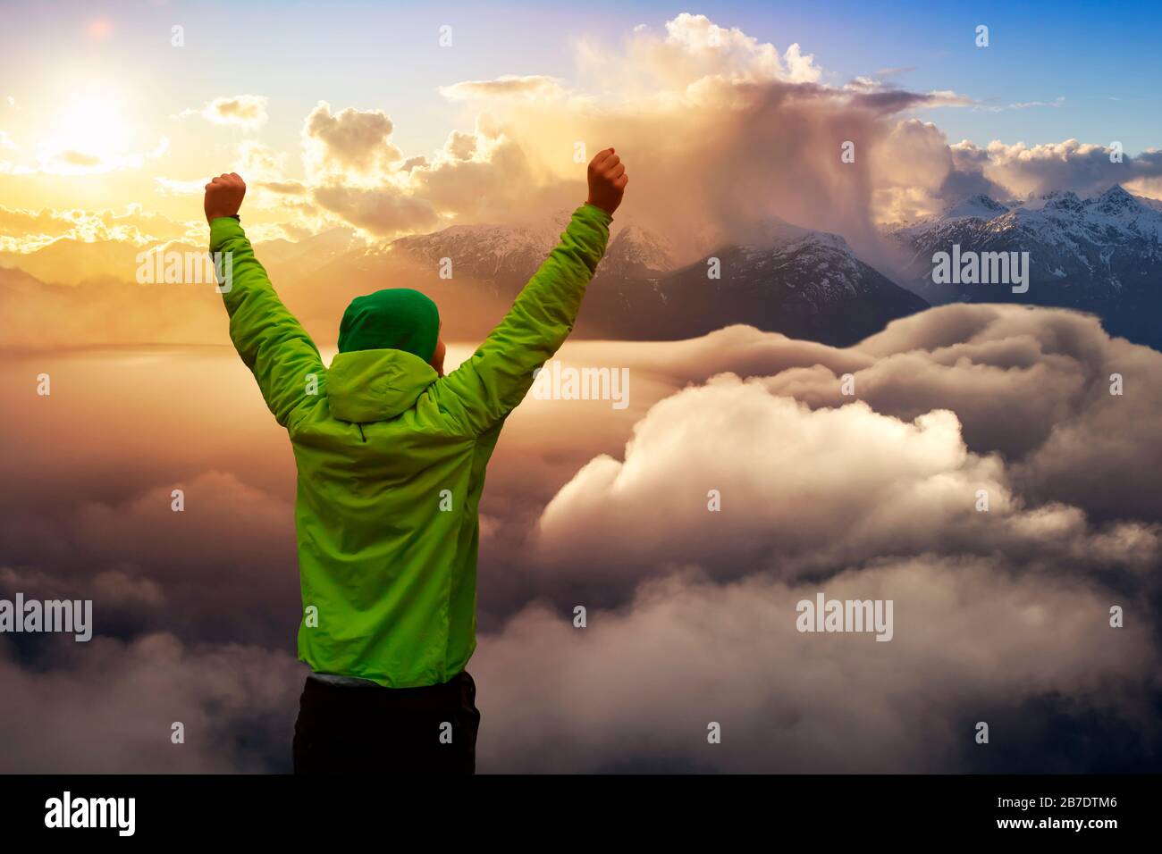 Adventurous friends on top of mountain with hands up during a colorful ...
