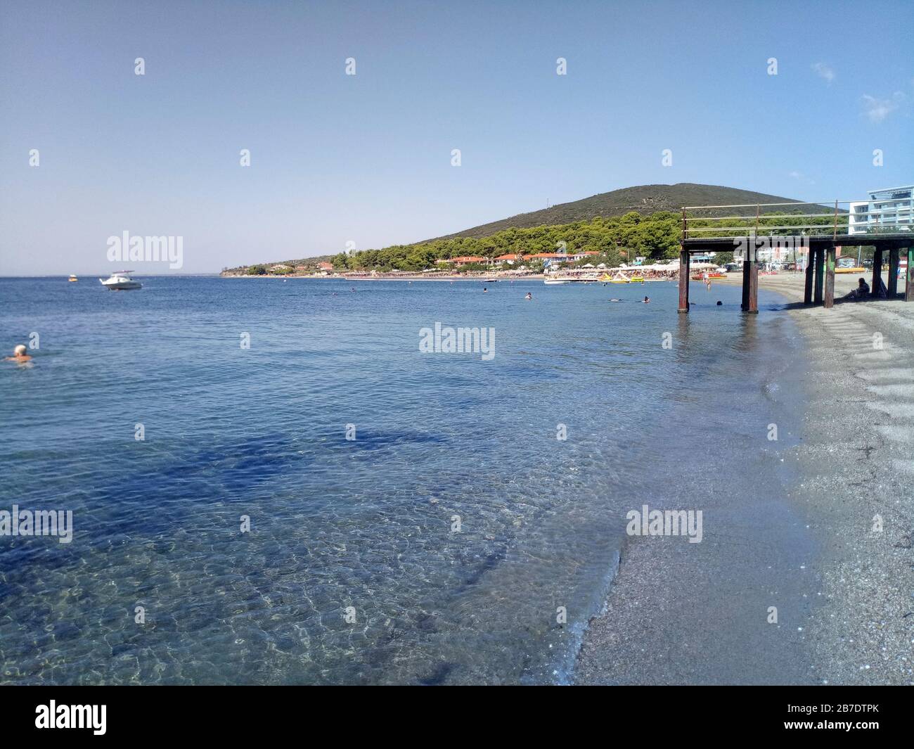 Psakoudia beach and seashore with dock in close and town in the back ...