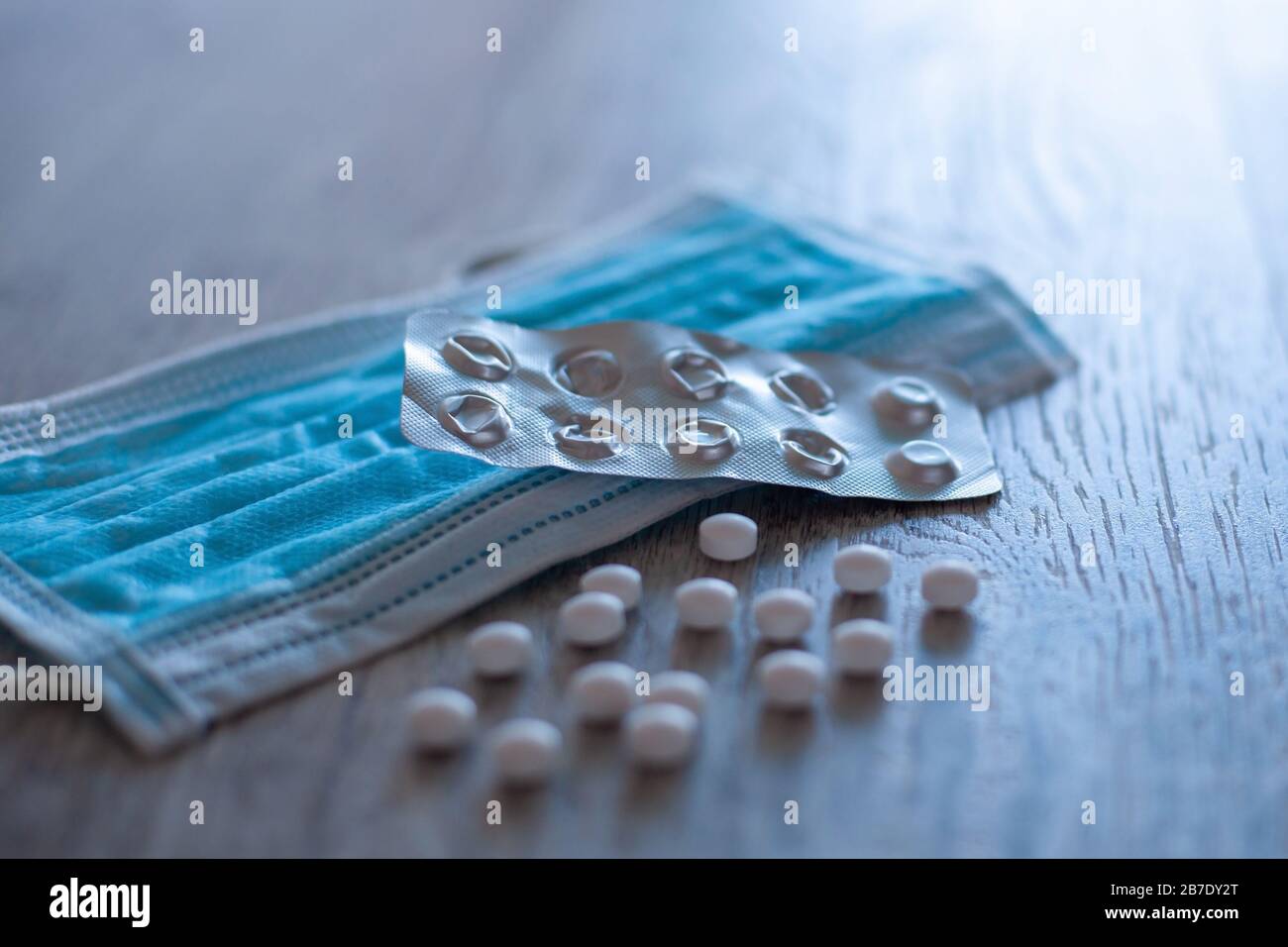 Medications in form of tablets, protective medical mask on light table ...